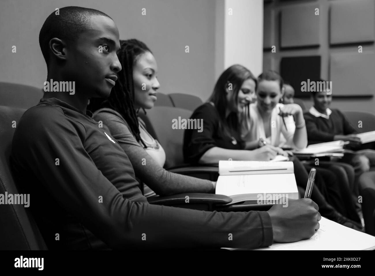A group of diverse students attentively listening and taking notes in a ...