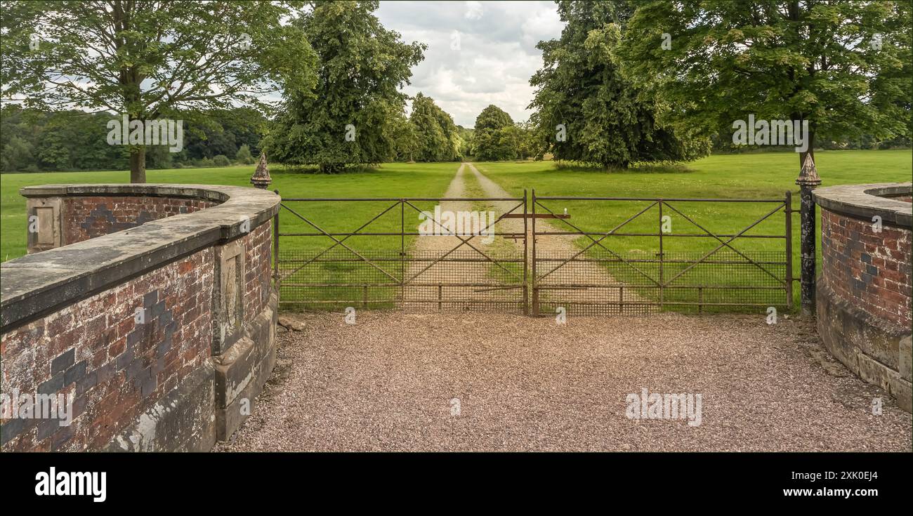 Looking at a gateway with closed metal gates down a pathway into a ...