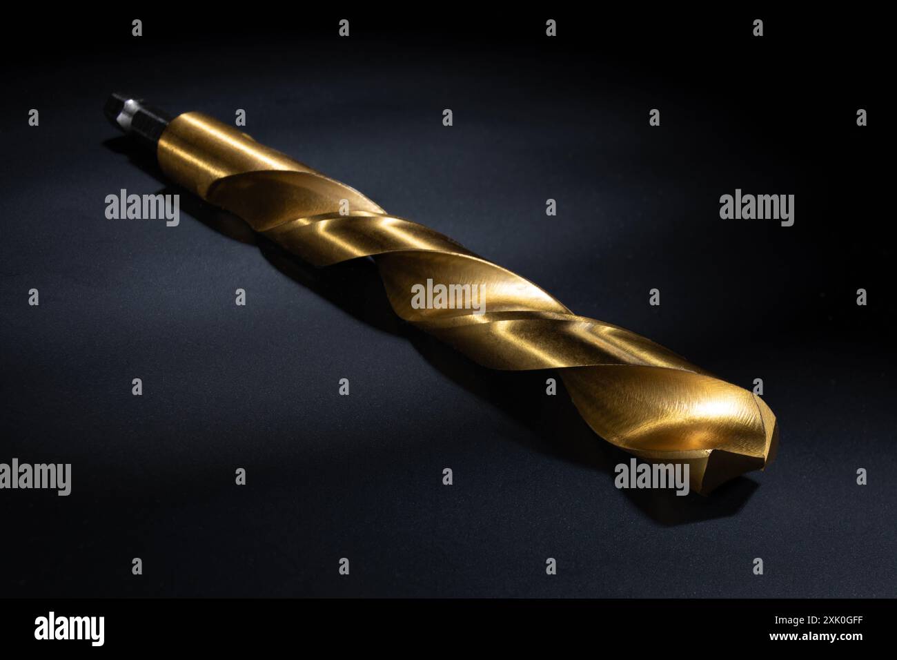 Large drill bit that has a hard copper colored coating on a black ...