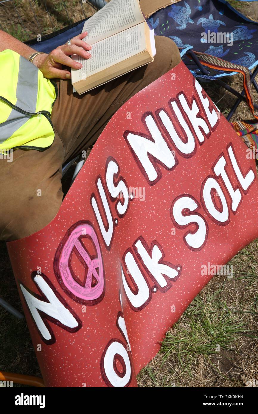 Lakenheath, England, UK. 20th July, 2024. A protester reads while ...