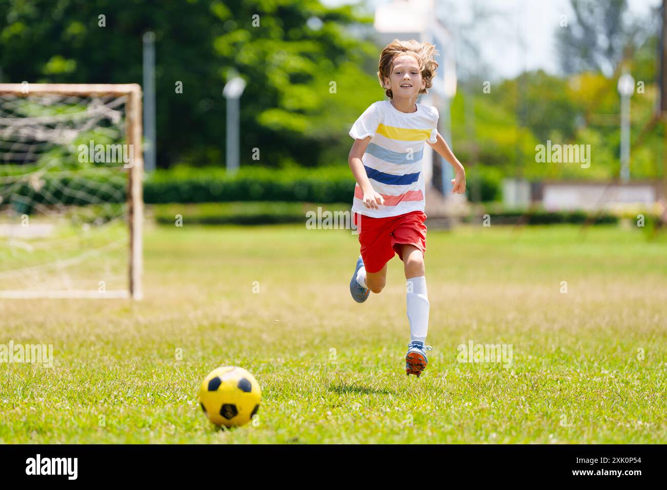 Child playing football. Kids play soccer on outdoor pitch. Little boy ...