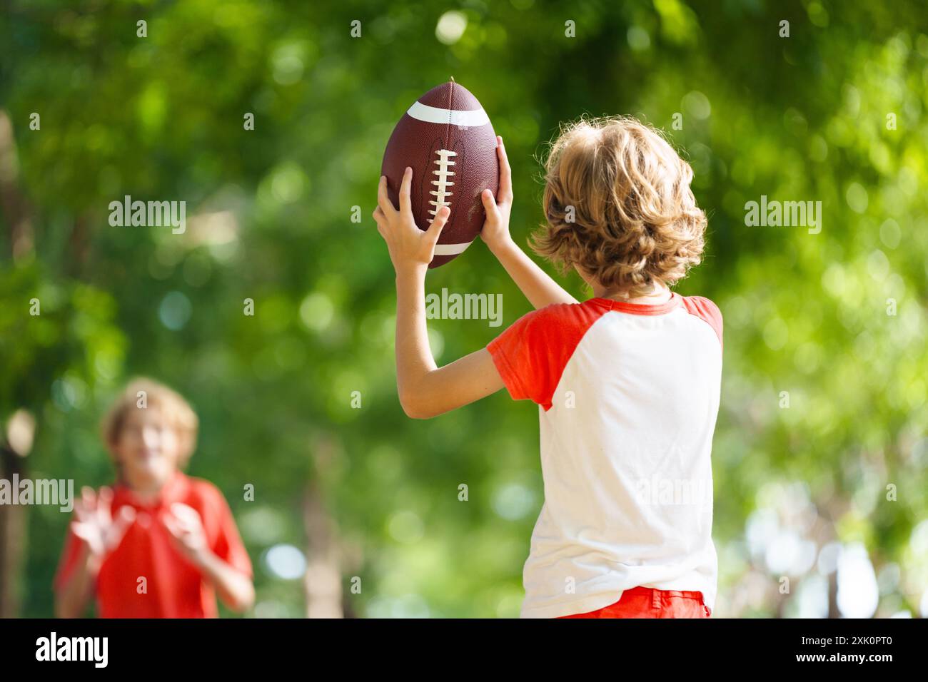 Family playing American football. Kids play rugby in sunny summer park ...