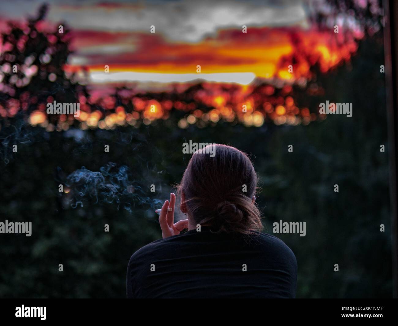 a woman smokes on the balcony watching colorful sunset Stock Photo - Alamy