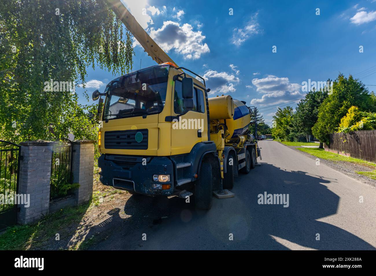 A large black and yellow concrete mixer mixes and pours concrete while ...