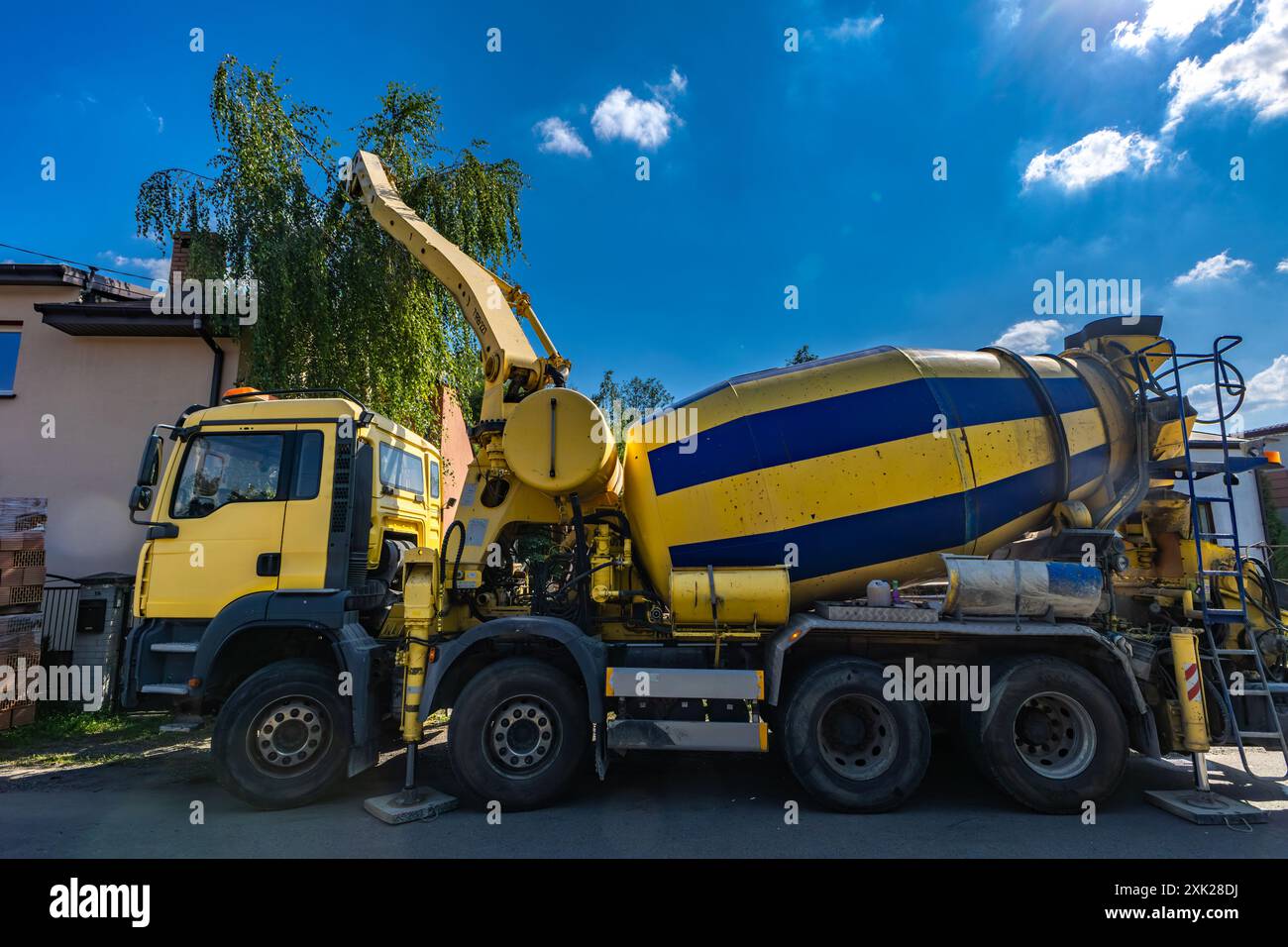 A large black and yellow concrete mixer mixes and pours concrete while ...