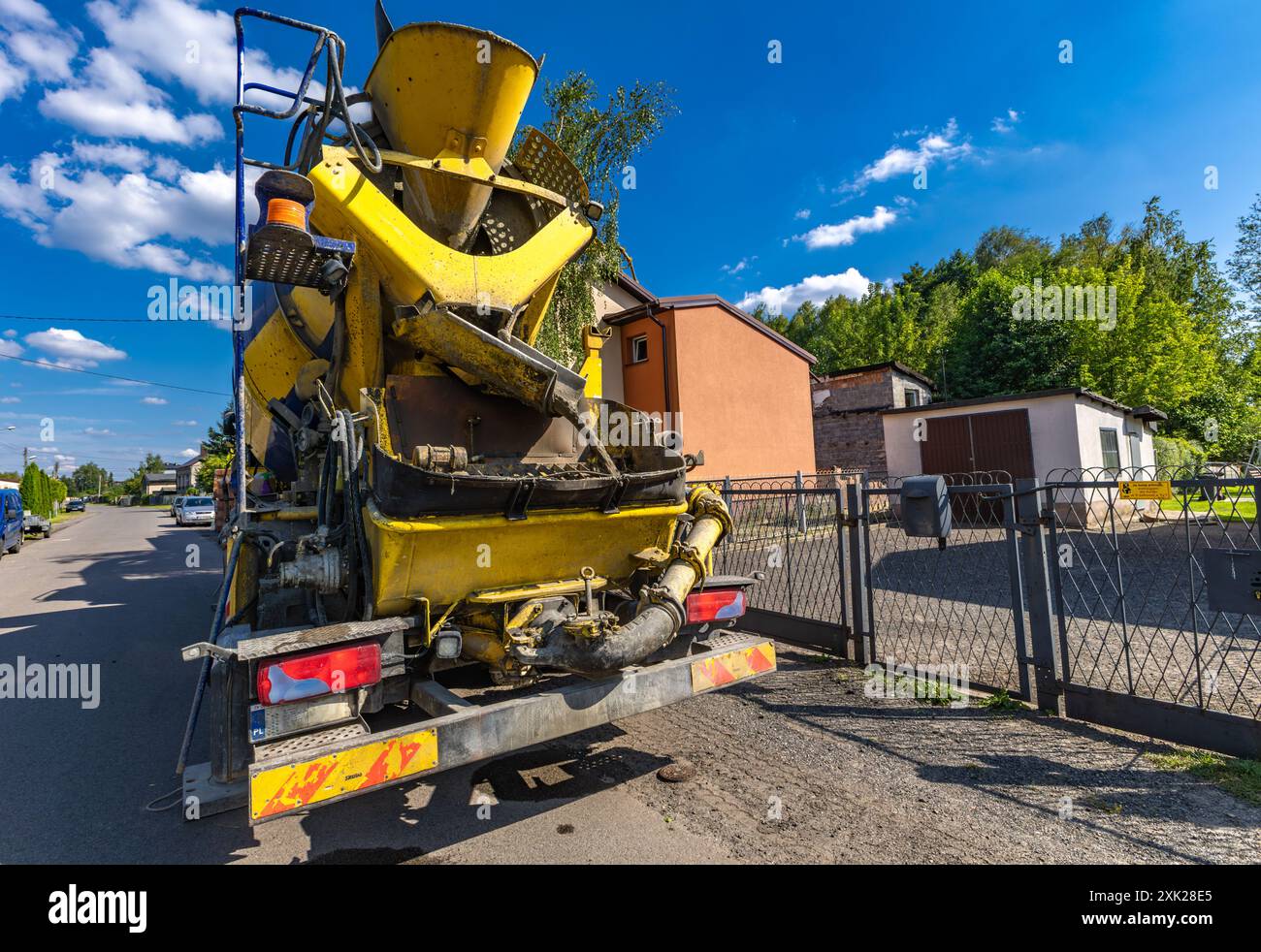 A large black and yellow concrete mixer mixes and pours concrete while ...