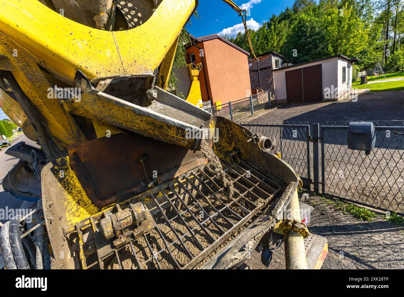 A large black and yellow concrete mixer mixes and pours concrete while ...