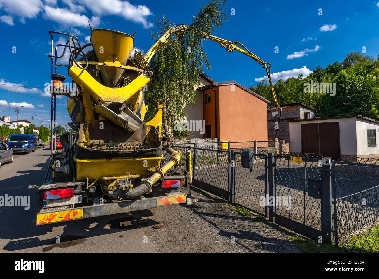 A large black and yellow concrete mixer mixes and pours concrete while ...