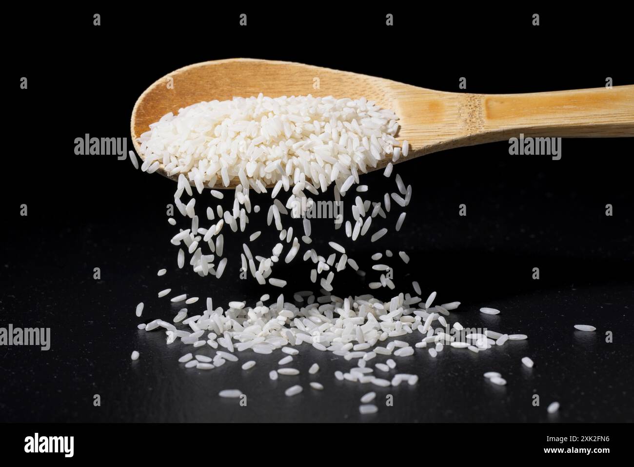 A conceptual photo of long grain white rice pouring off a wooden spoon ...