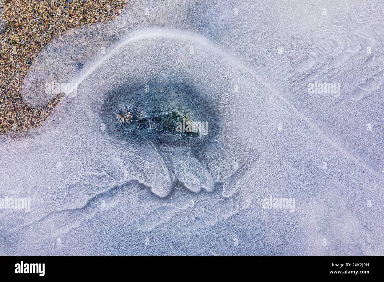 A vivid aerial view of a colorful pebble encased in cracked, textured ...