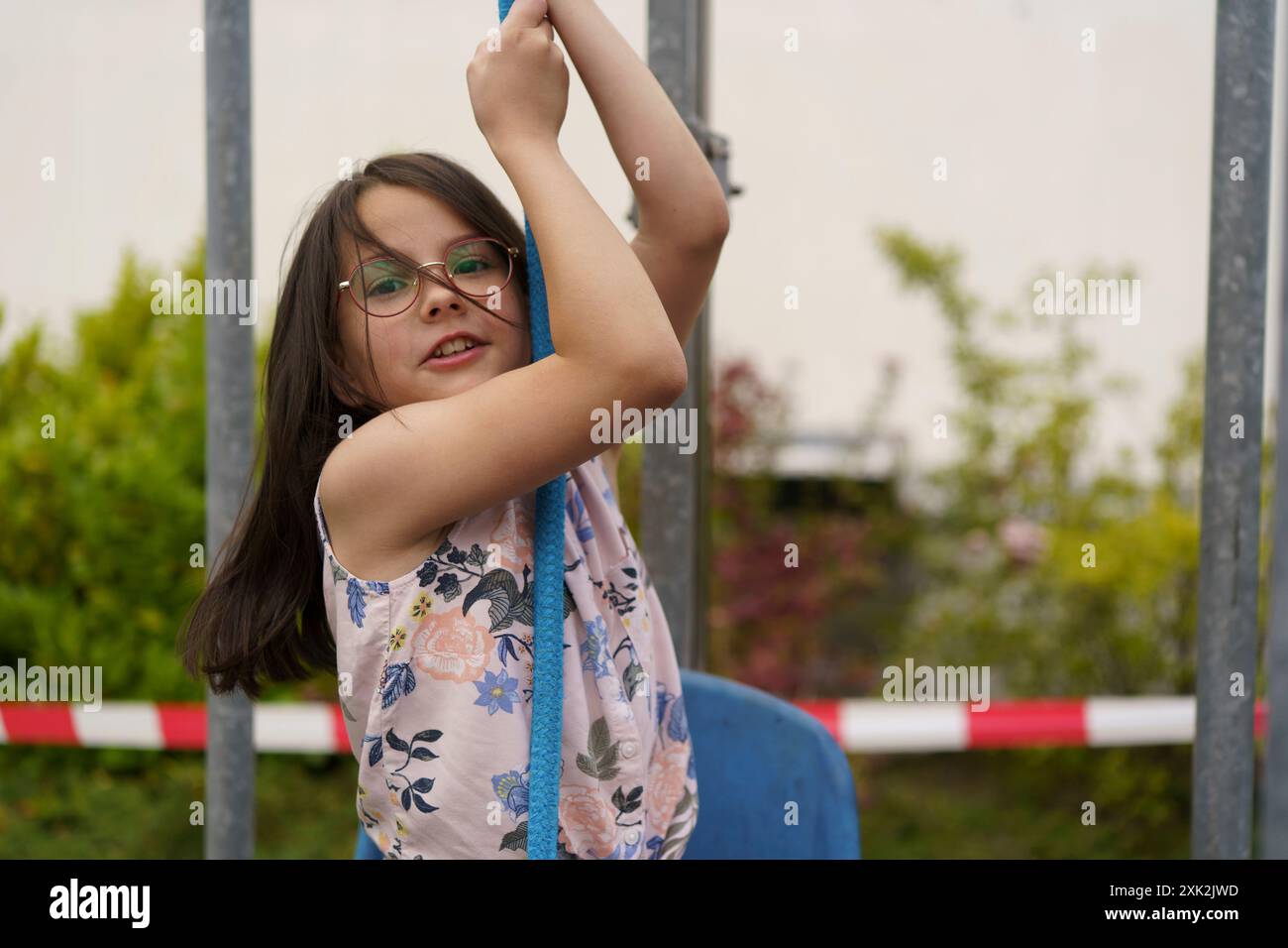 A little girl pulls a rope trying to lift herself in a chair. Concept ...