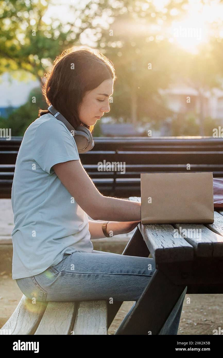 Side view of a young woman concentrates on writing in her notebook ...