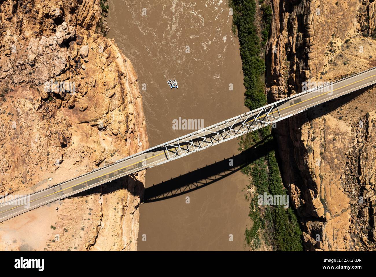 Aerial shot of a steel bridge spanning across the muddy waters of a ...