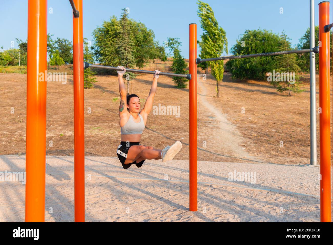 Fit young woman exercises on horizontal bars in an outdoor street gym ...