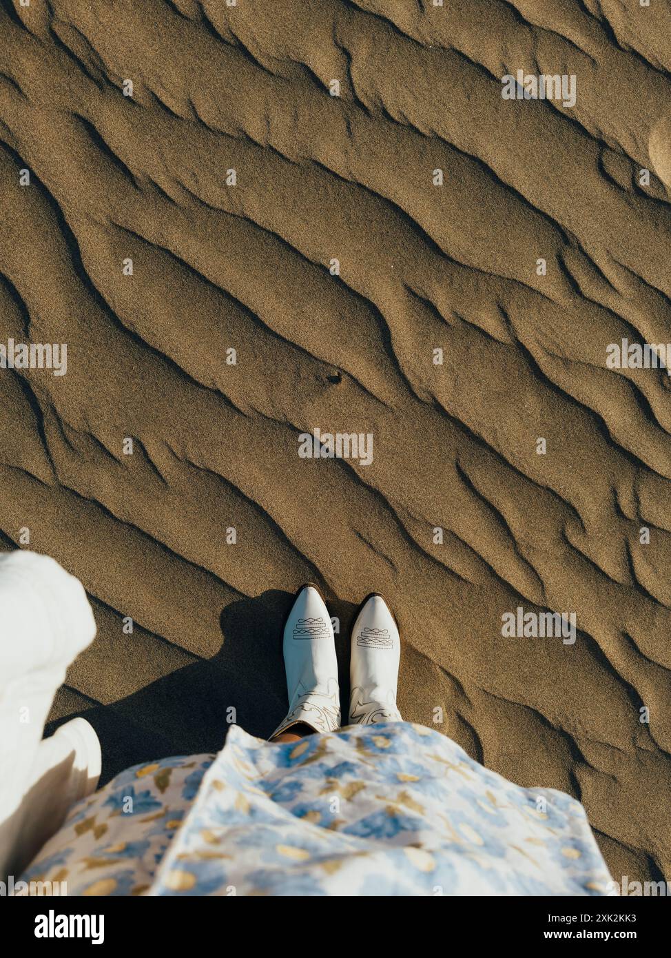 A top-down view captures a woman's feet dressed in stylish white boots ...