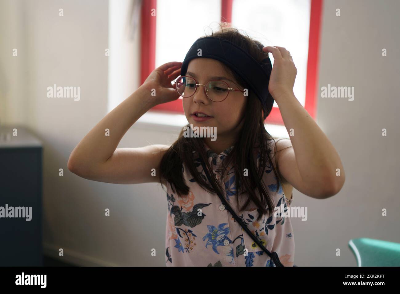 A little girl wearing a sensor headband that measures brain activity ...