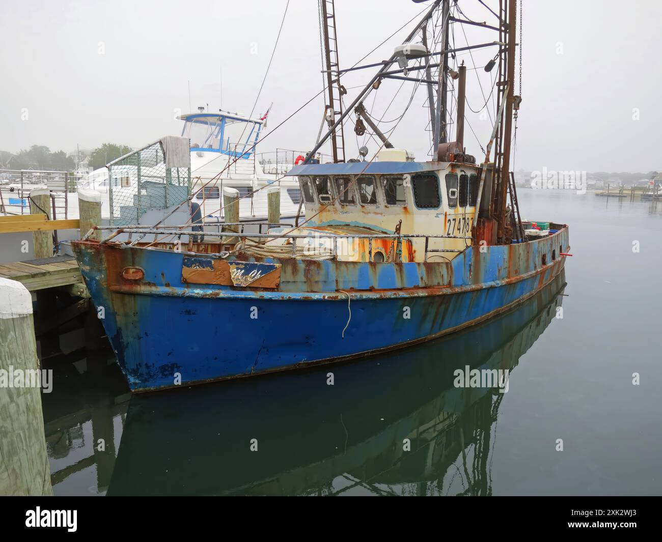 Old rusted blue boat at dock with some background fog,in Hyannis Harbor ...