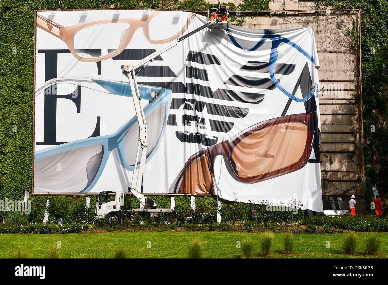 Workers putting up a maxi advertising billboard of the fashion brand ...