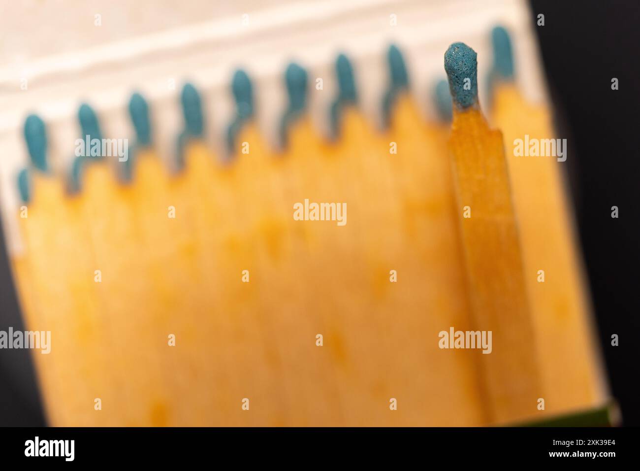A blue match head focused on a blurred background of blue cardboard ...