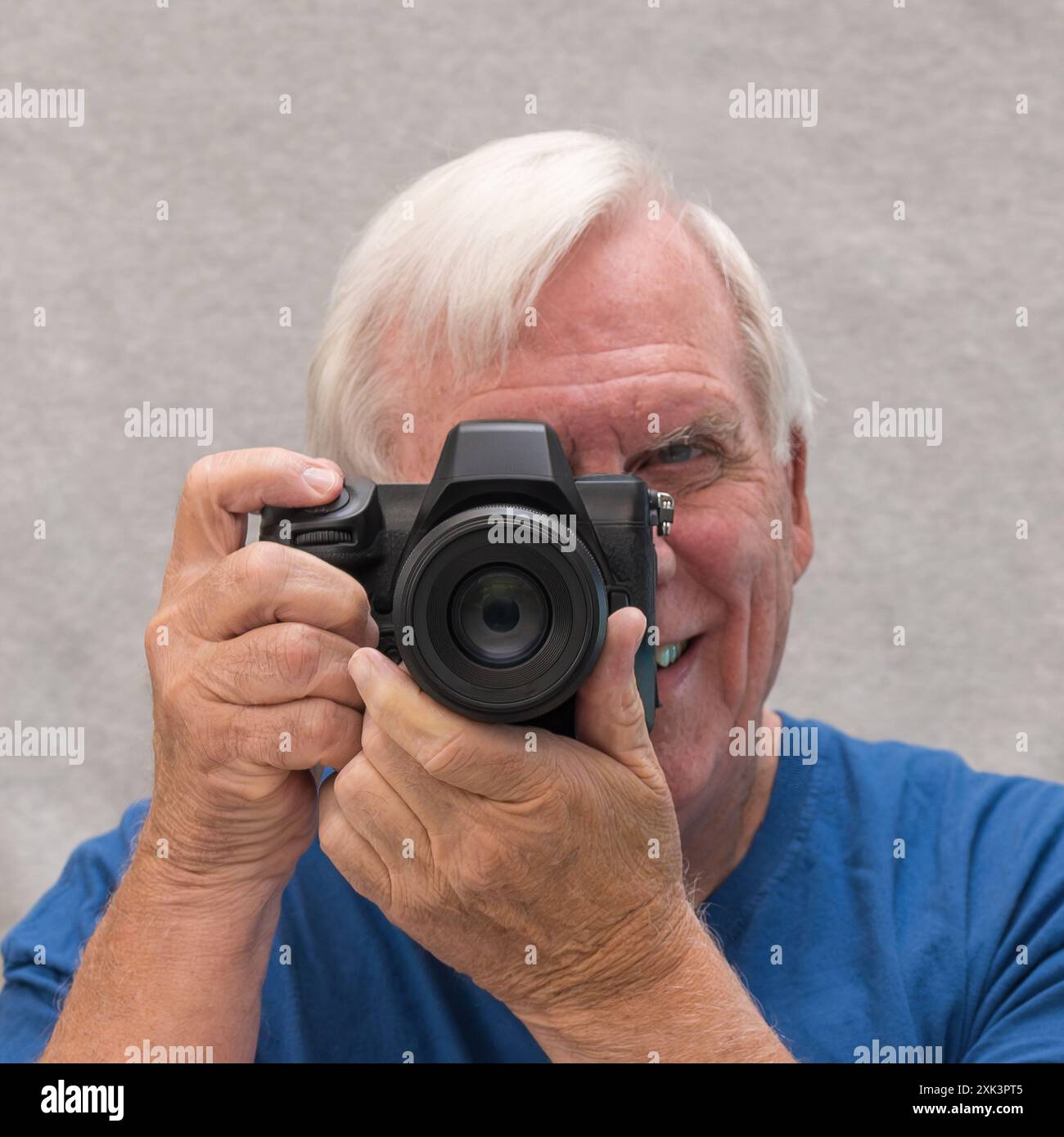 Older man looking through camera viewfinder and smiling Stock Photo - Alamy