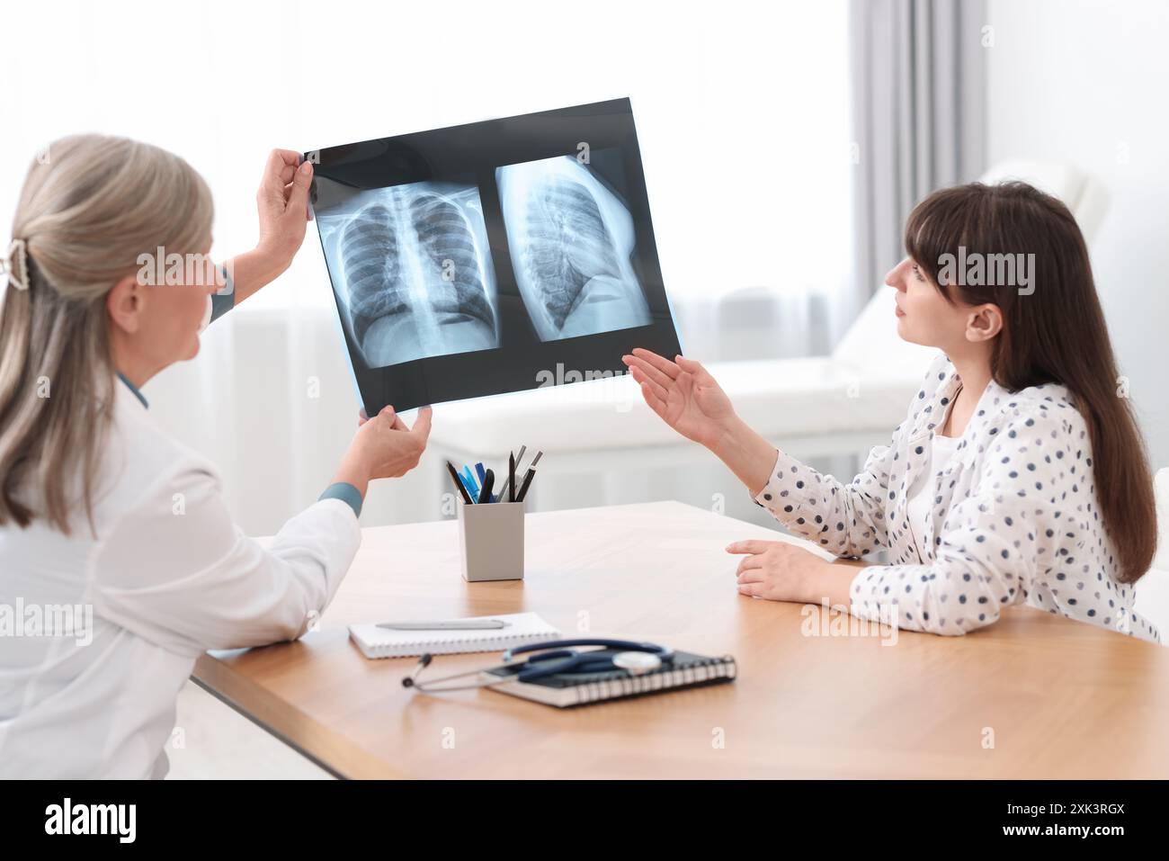 Lung disease. Doctor showing chest x-ray to her patient in clinic Stock ...