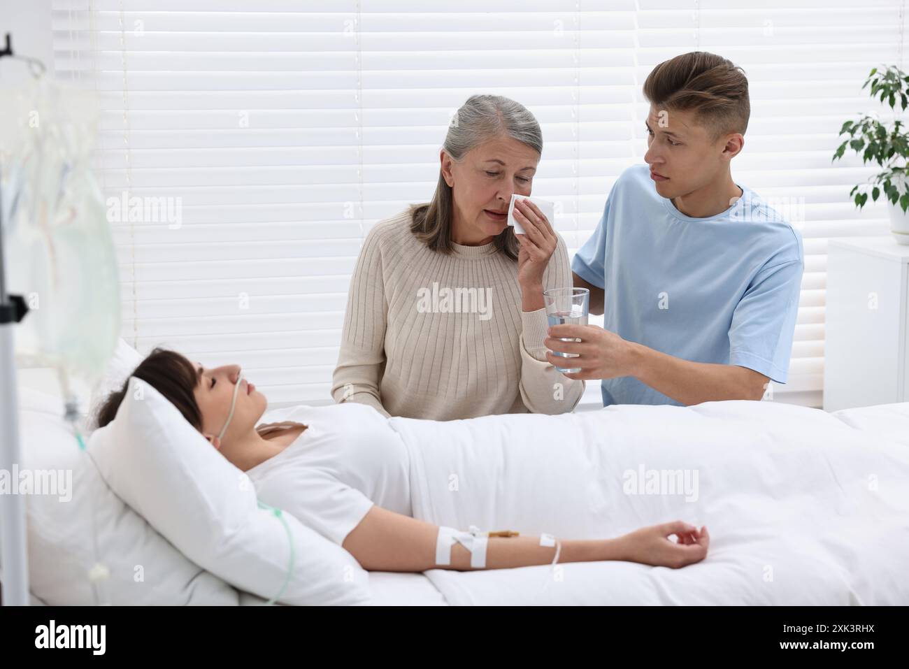 Coma patient. Sad relatives near sleeping young woman in hospital Stock ...