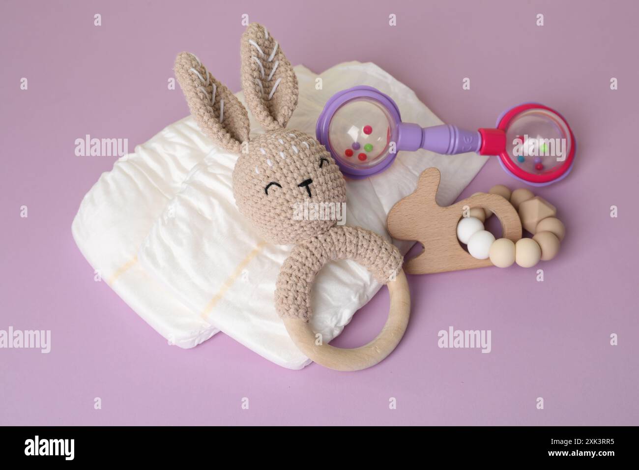 Baby rattles and diapers on lilac background Stock Photo - Alamy