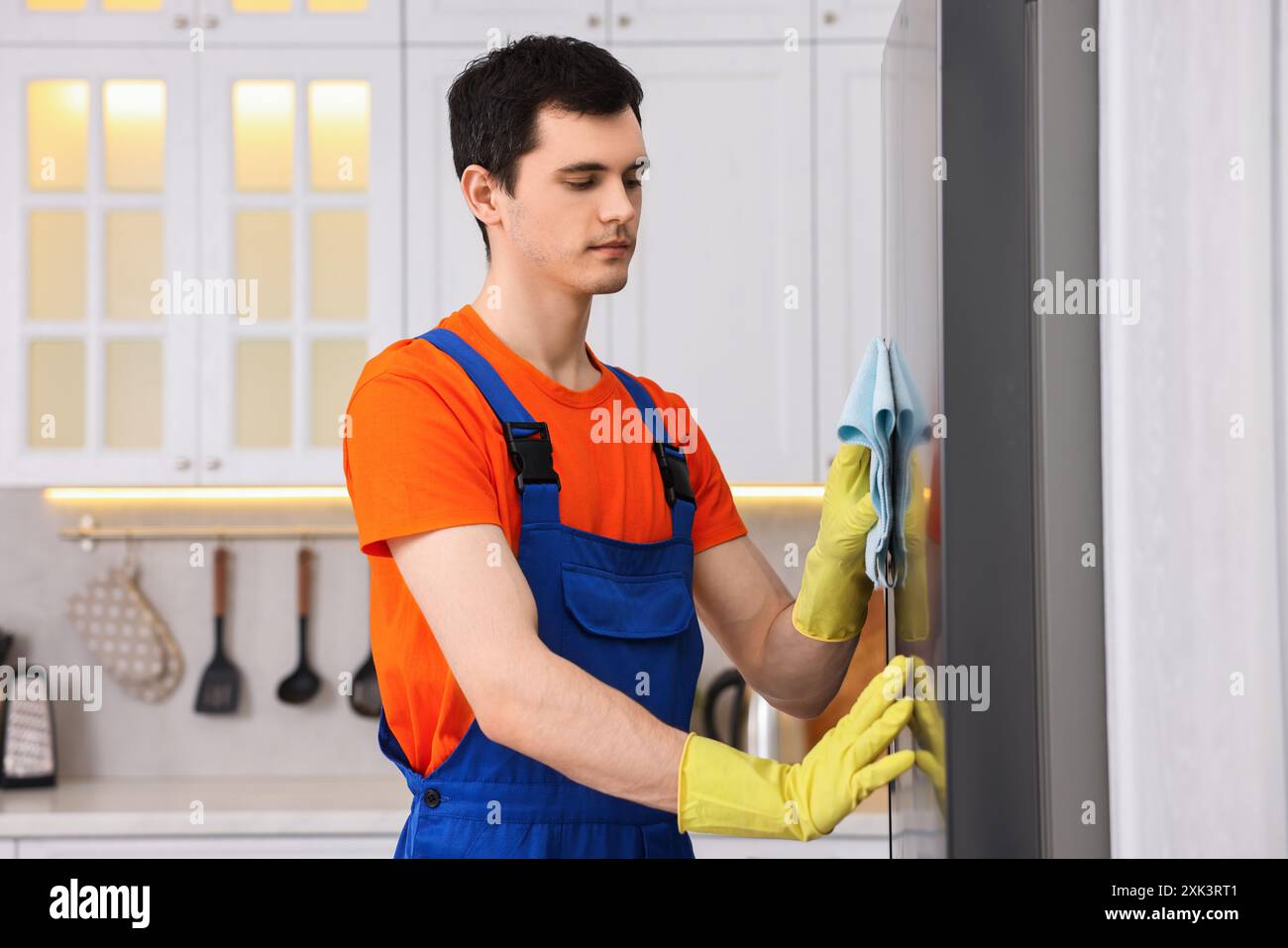 Professional janitor wearing uniform cleaning fridge in kitchen Stock ...