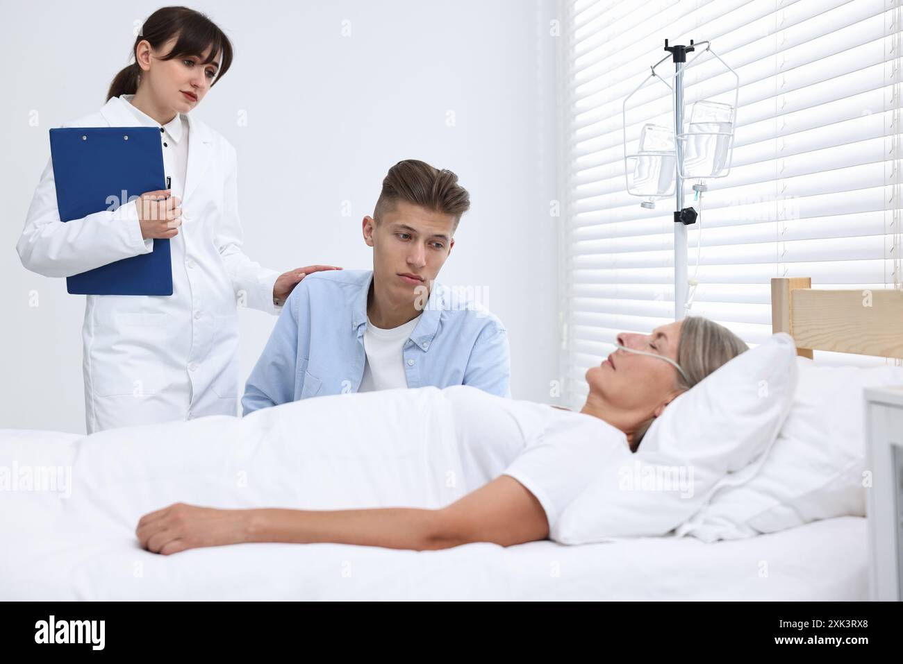 Coma patient. Sad young man near his unconscious mother talking with ...