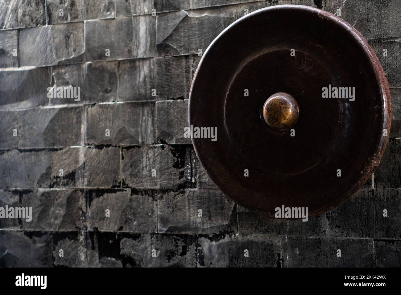 A close-up of a dark, textured wall made of slate tiles, featuring a ...