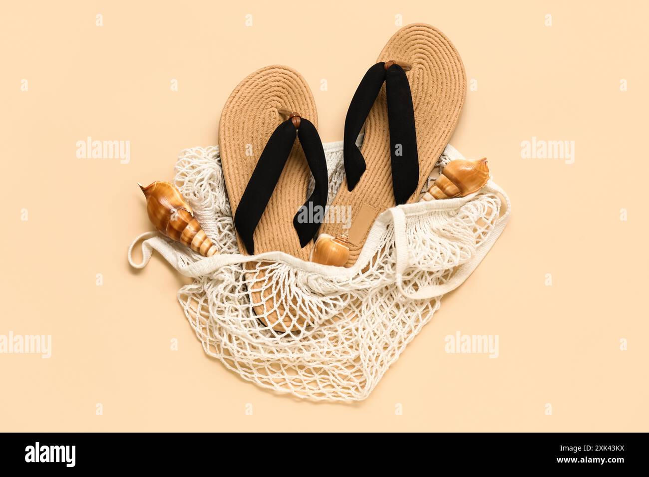 String bag with flip flops and seashells on beige background Stock ...