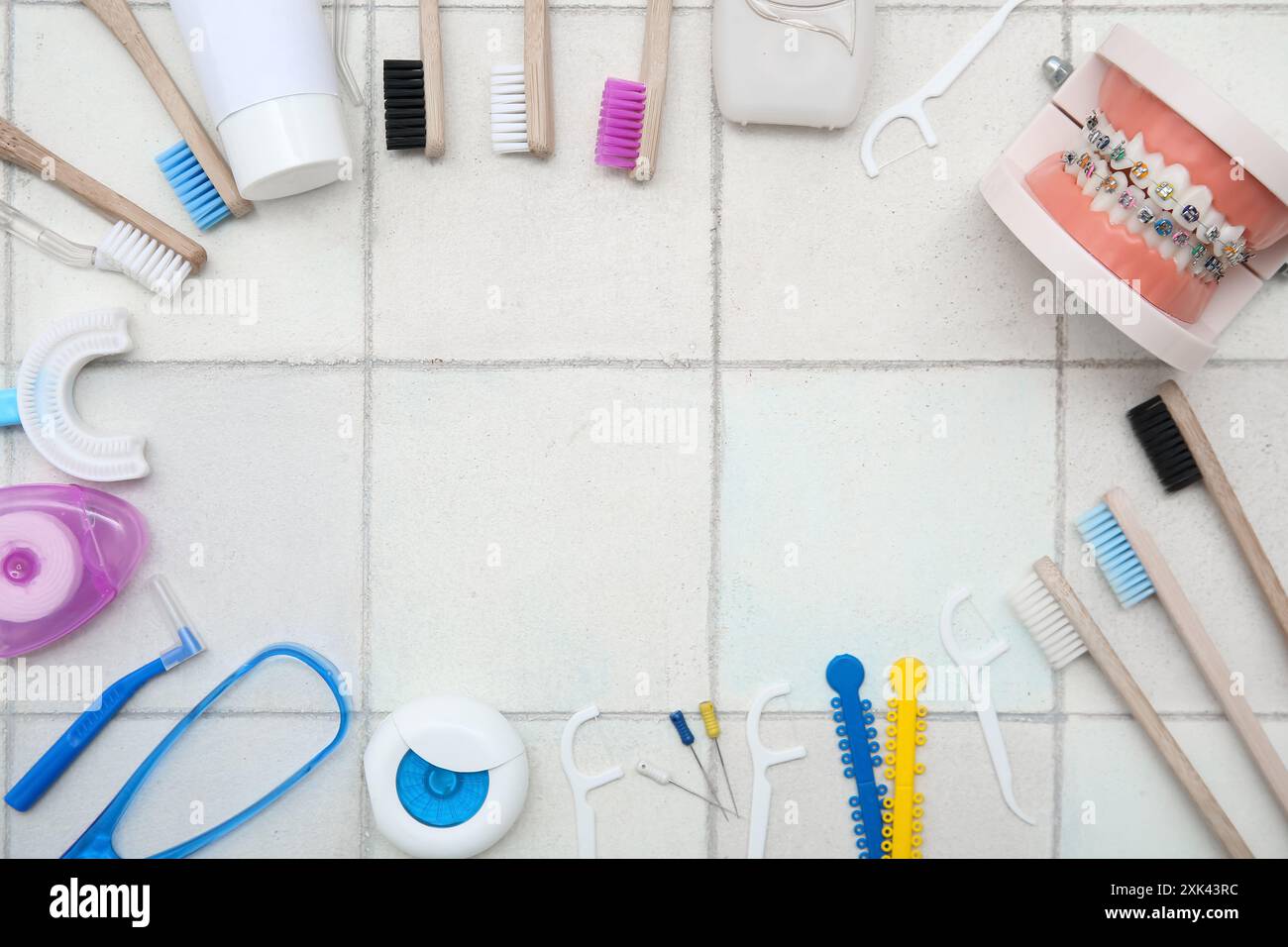 Frame made of set for oral hygiene and jaw model on tile background ...