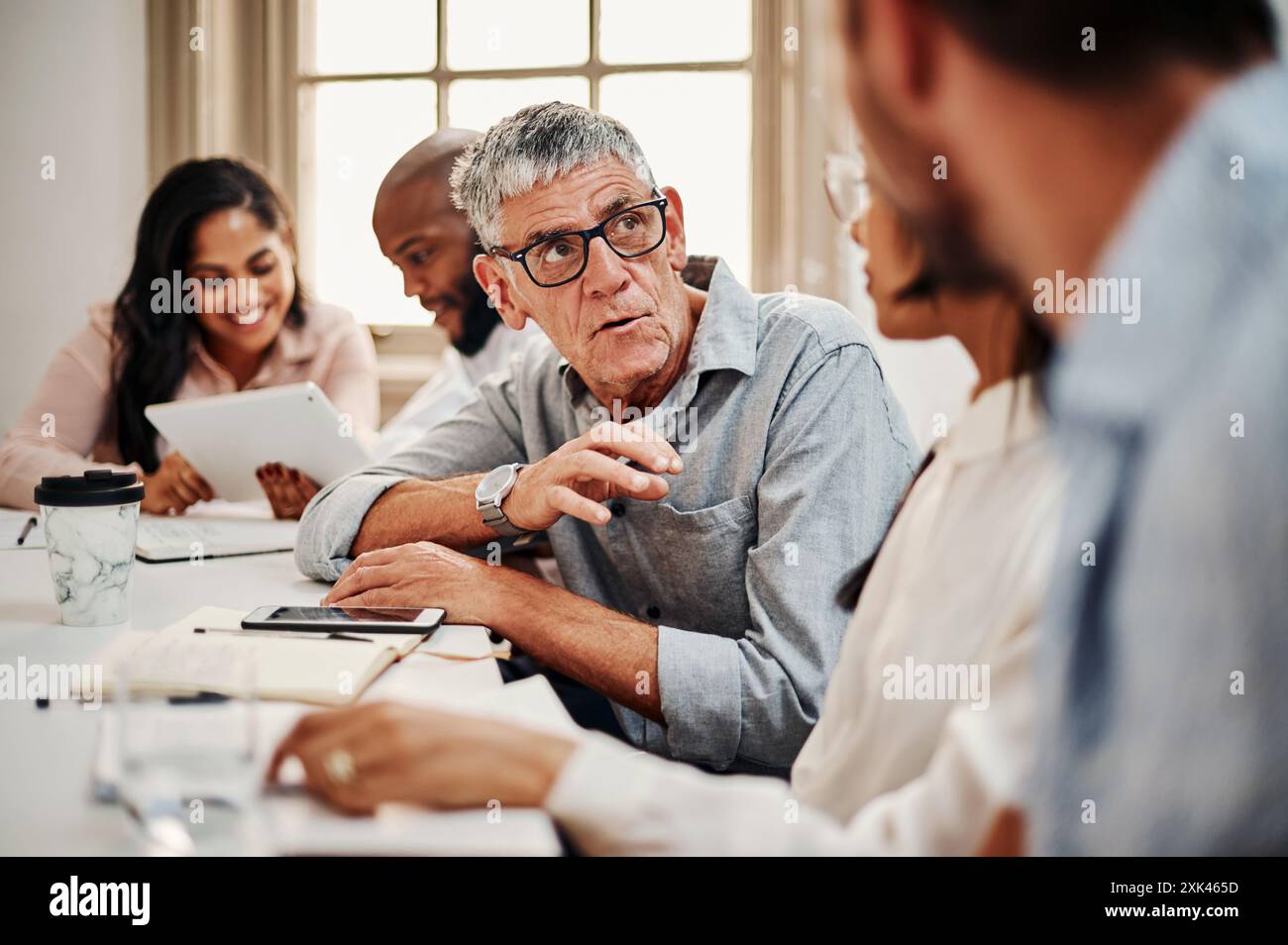 Mature businessman, mentor and meeting with creative team for project ...