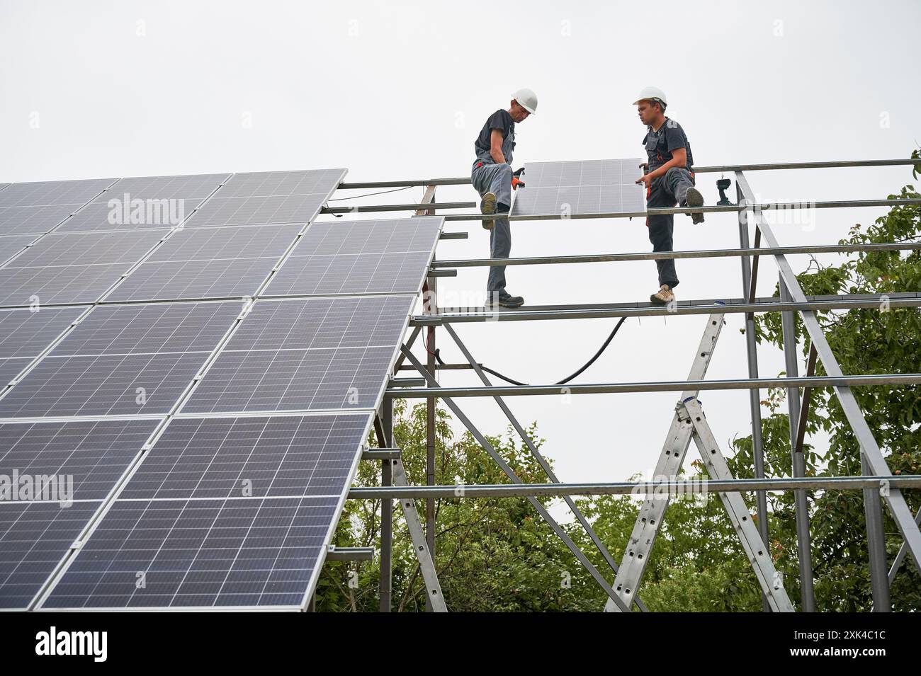 Workers installing solar panels on metal beams. Men wear helmets and ...
