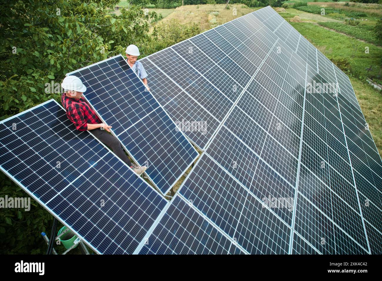 Workers installing solar panels in field. European men in helmets and ...