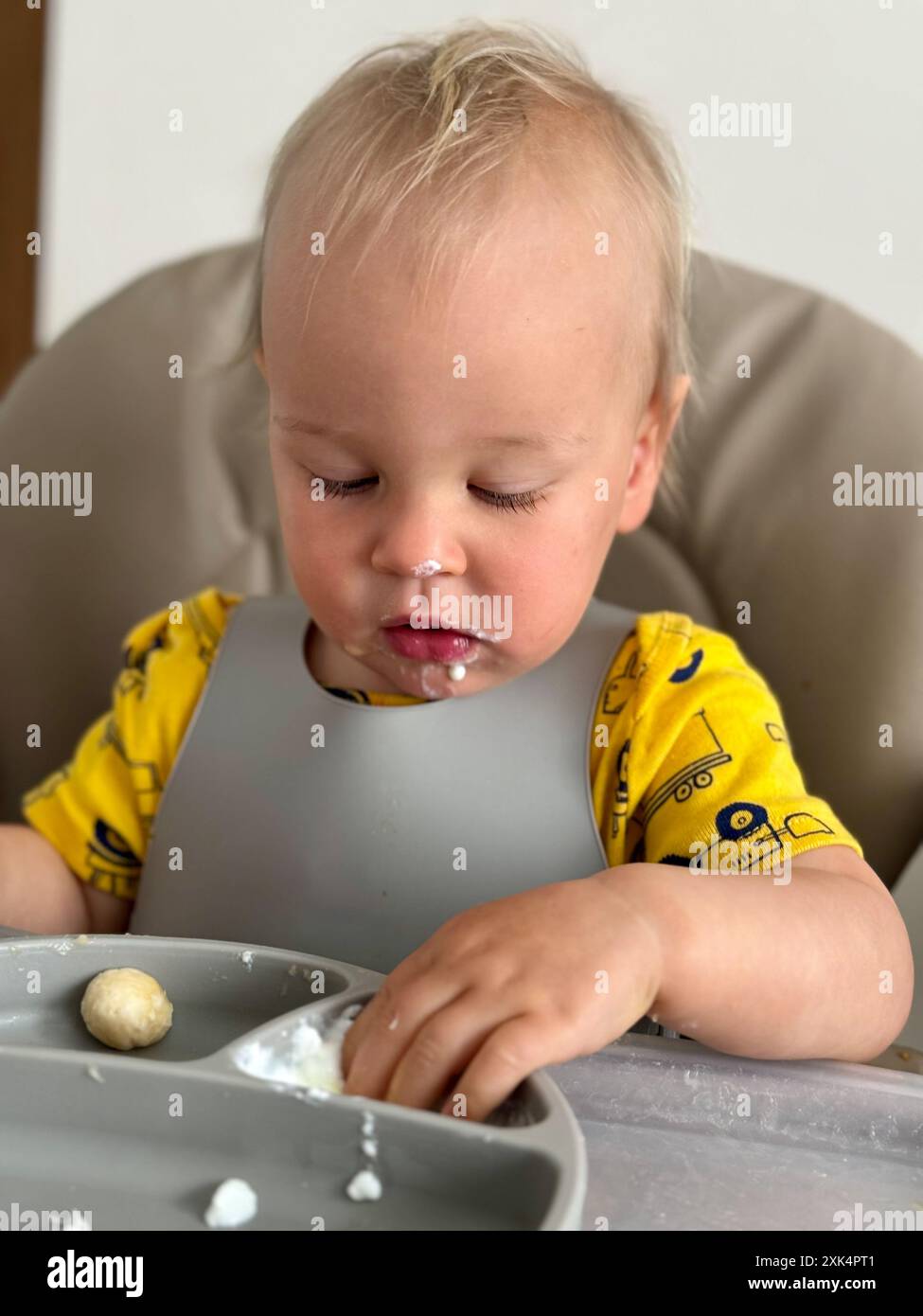 Baby eating his food with hands and spoon Stock Photo - Alamy