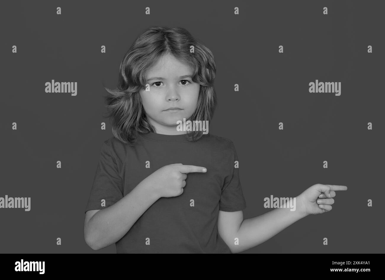 Child in red t-shirt pointing finger away on yellow isolated studio ...