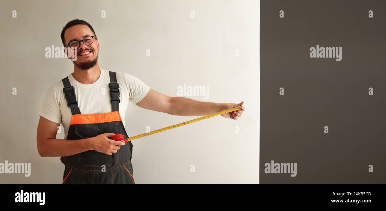 Construction site with worker holding measuring tape, safety overall ...