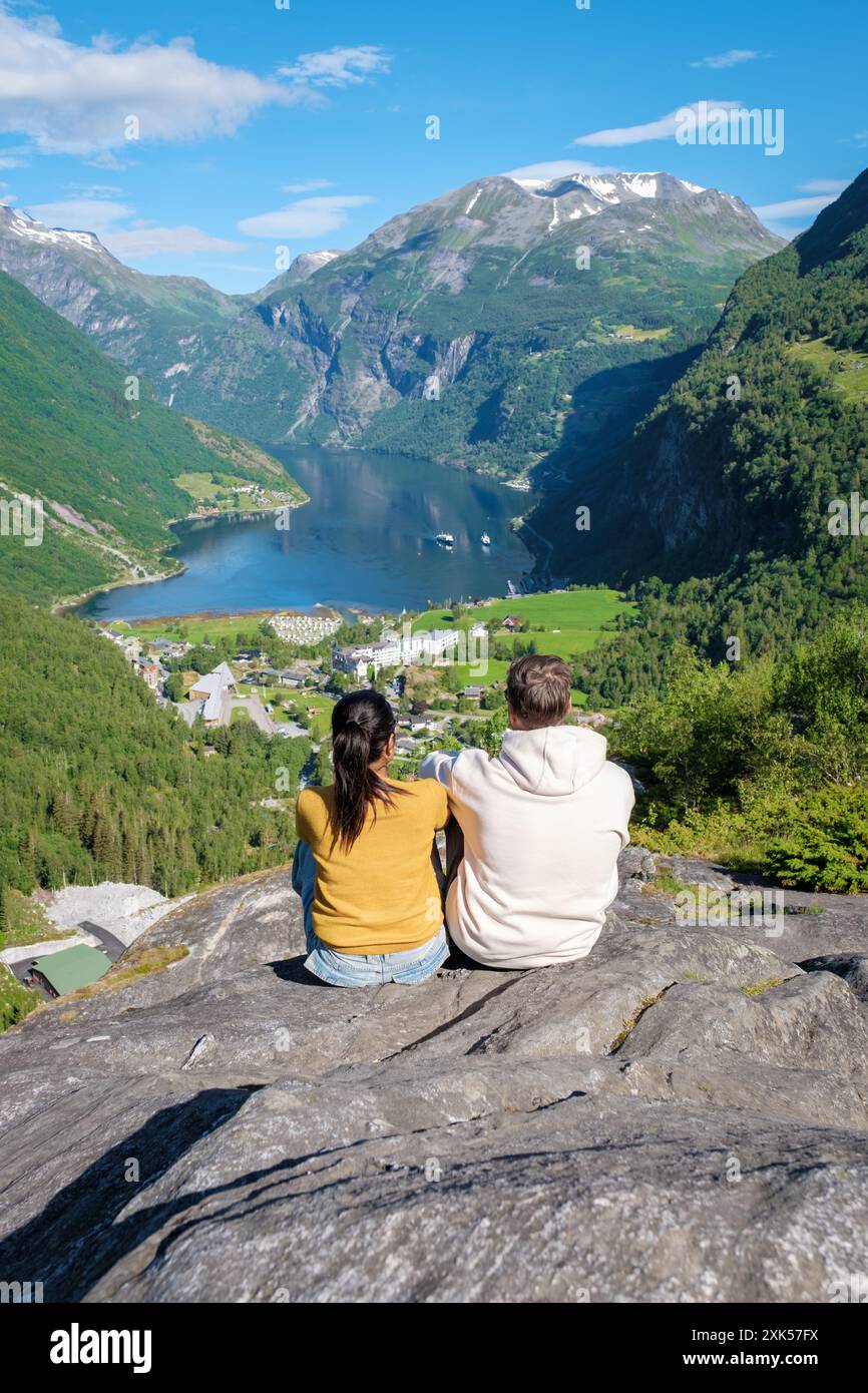 A couple sits on a rocky outcrop, gazing out at a stunning Norwegian ...