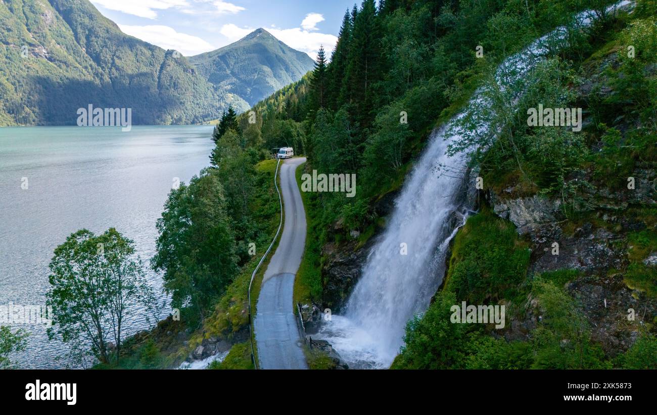 A winding road snakes through lush greenery, passing by a powerful ...