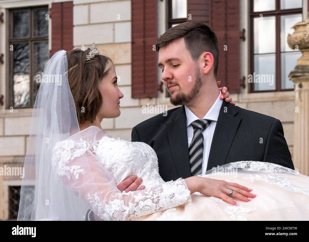 The groom gently holds the young bride in his arms. Close-up. Love ...