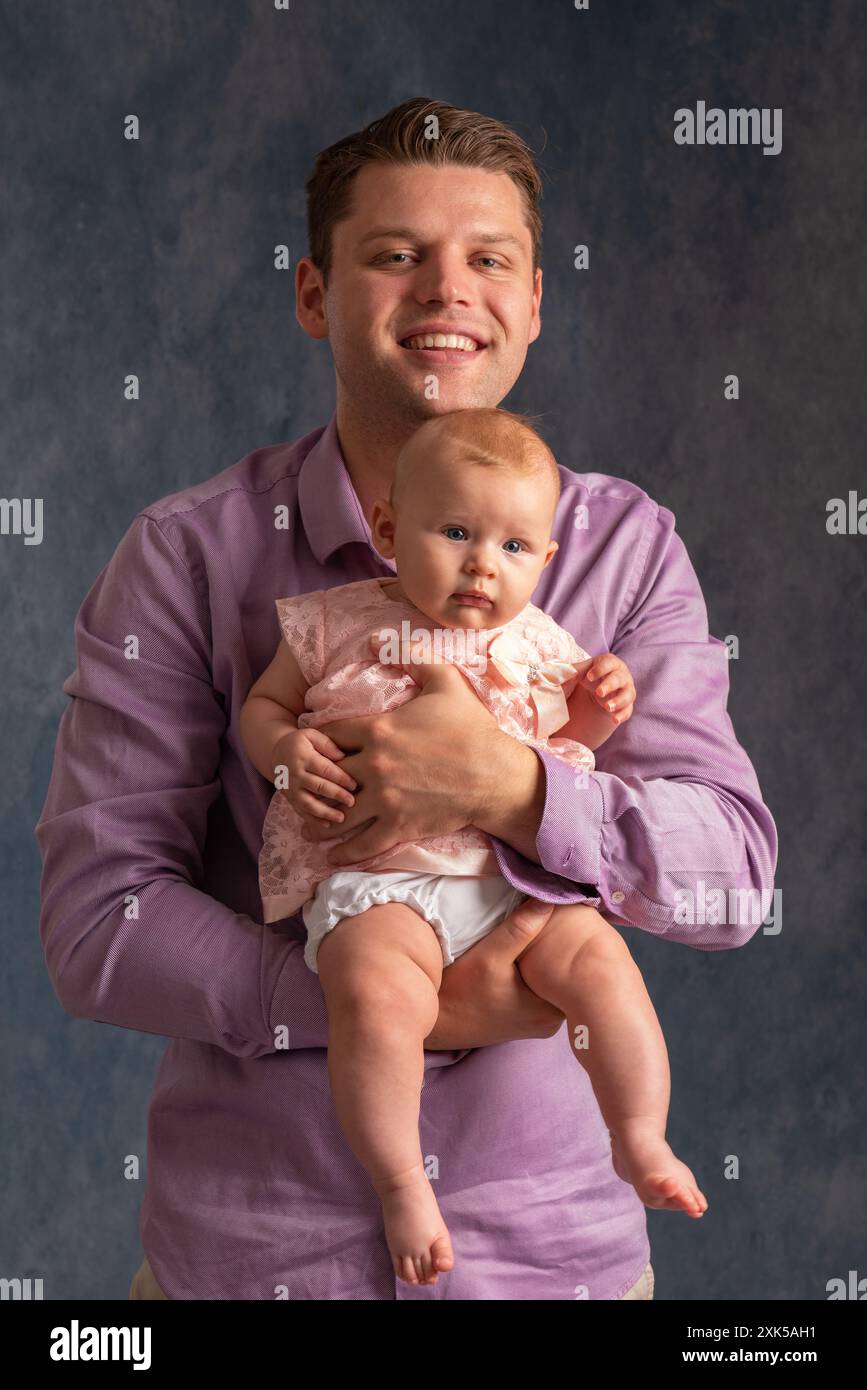 A young dad gently holds his daughter in his arms. pride in being a ...