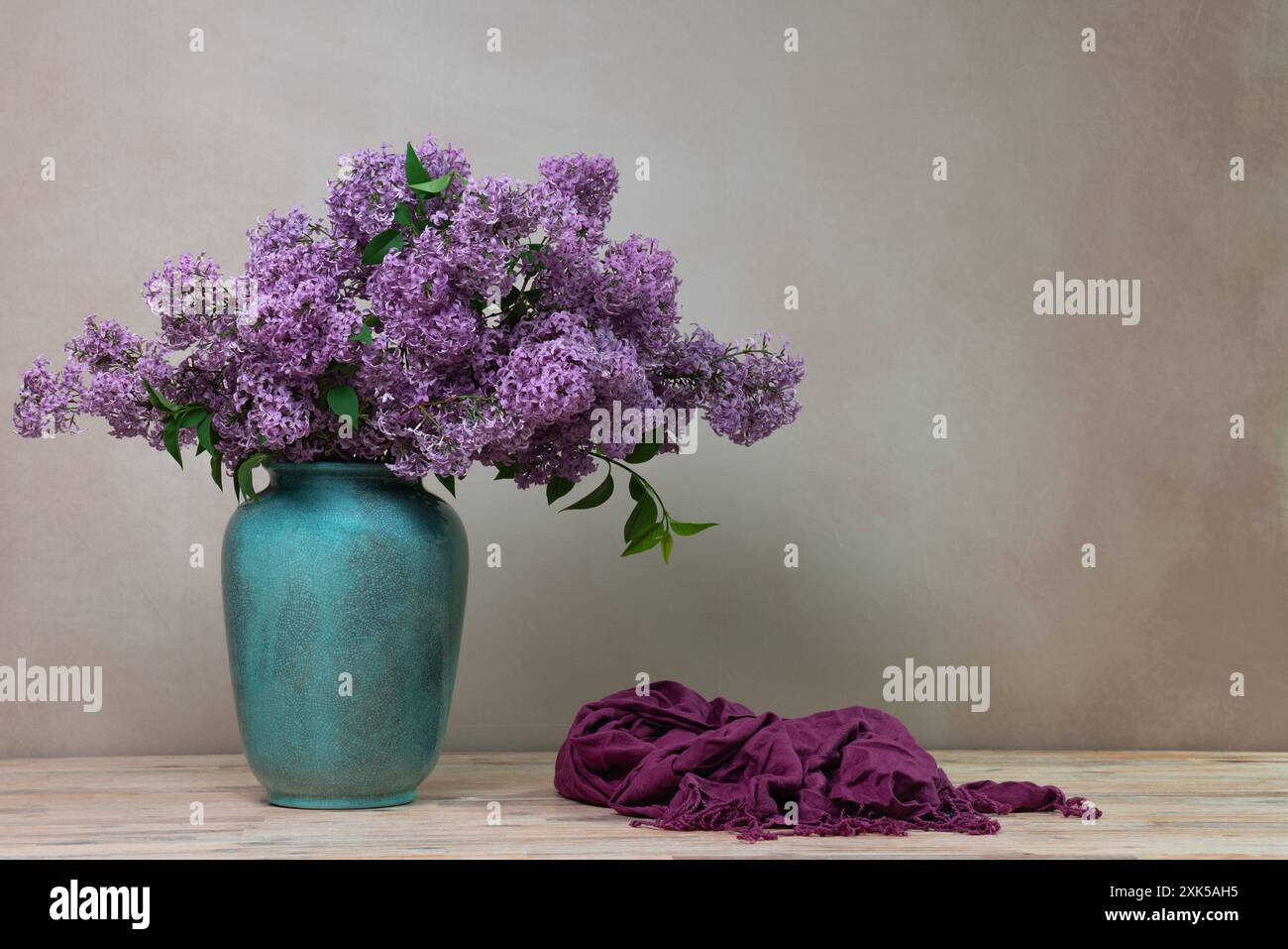 A large bouquet of lilacs in a turquoise vase on a light background ...
