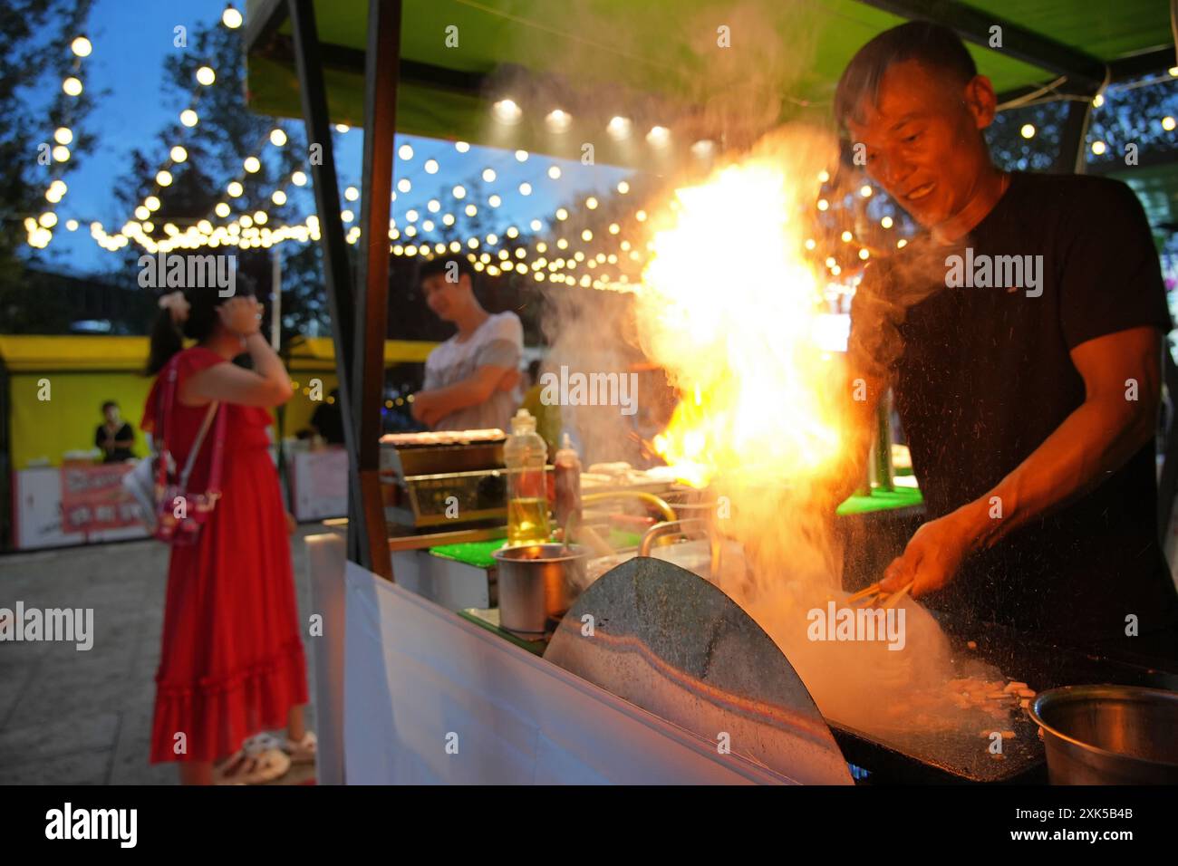 YANTAI, CHINA - JULY 20, 2024 - A vendor makes grilled squid at a ...