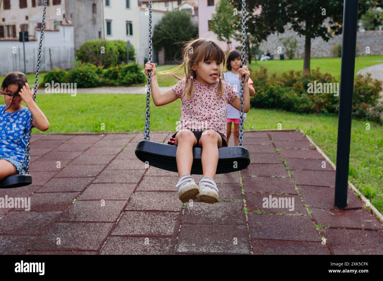 three children playing with swings in public park Stock Photo - Alamy