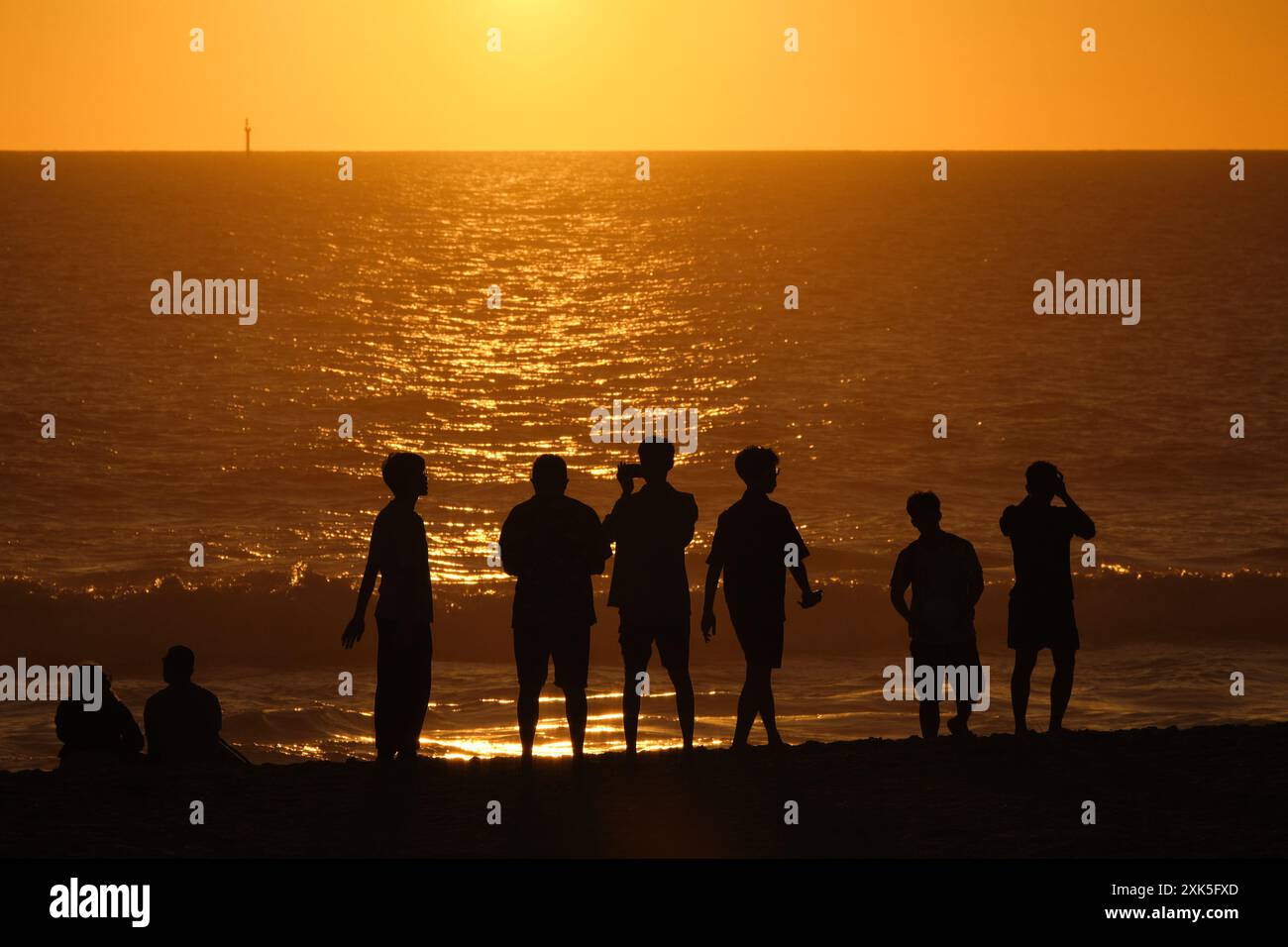 Young people in silhouette enjoying the sunset with golden light at ...
