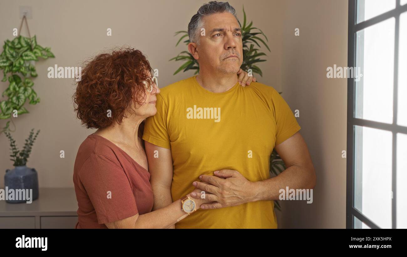 Middle-aged couple embracing in a cozy living room, with the woman ...