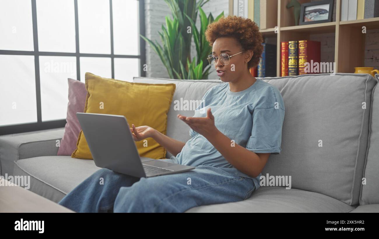 An attractive black woman in casual clothing is having a video call at ...