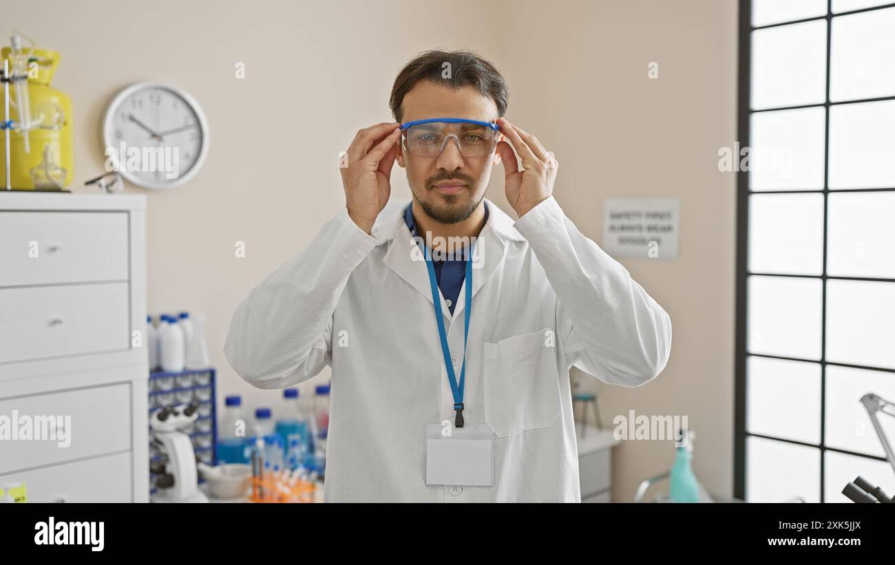 Hispanic man in lab coat adjusting safety goggles in a bright ...