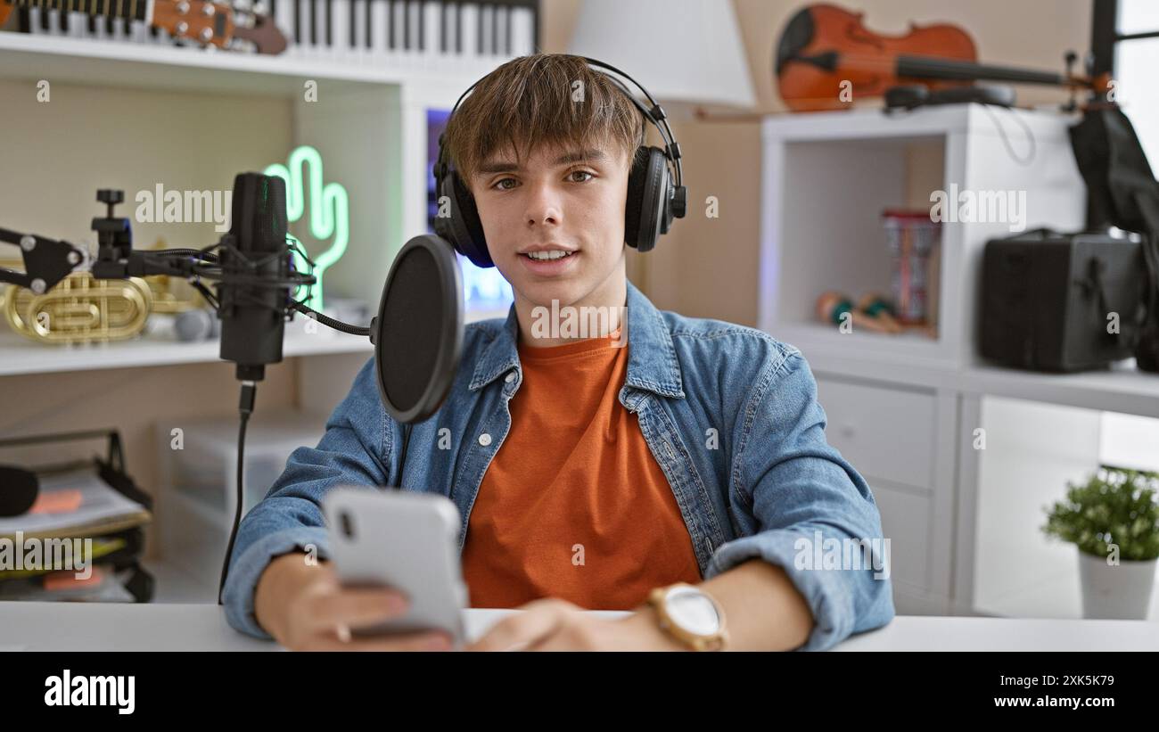 A youthful male podcaster with headphones interacts with his smartphone ...